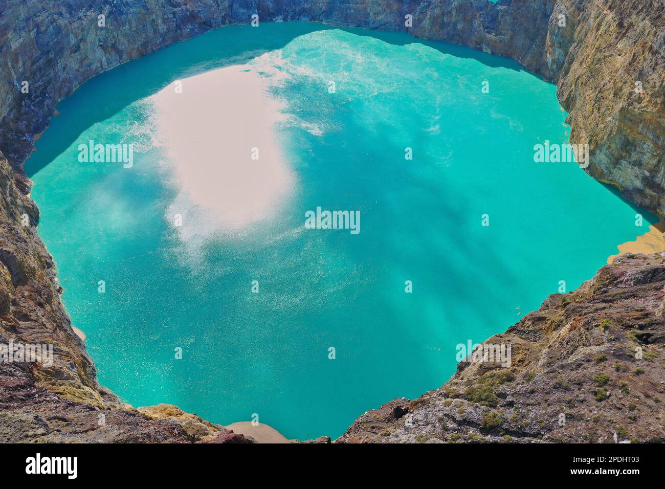 Bird's eye view of the sunlit turquoise crater lake of Mount Kelimutu ...