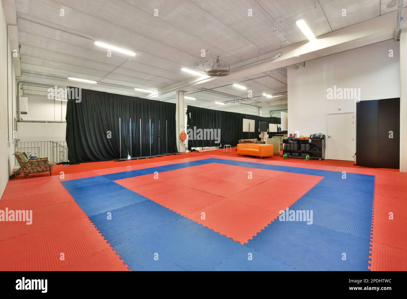 a room with red, blue and white mats on the floor in front of a black ...