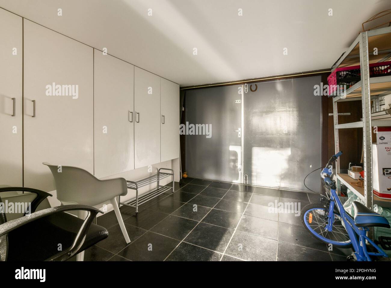 a room with white cabinets and black tiles on the floor there is a bike ...