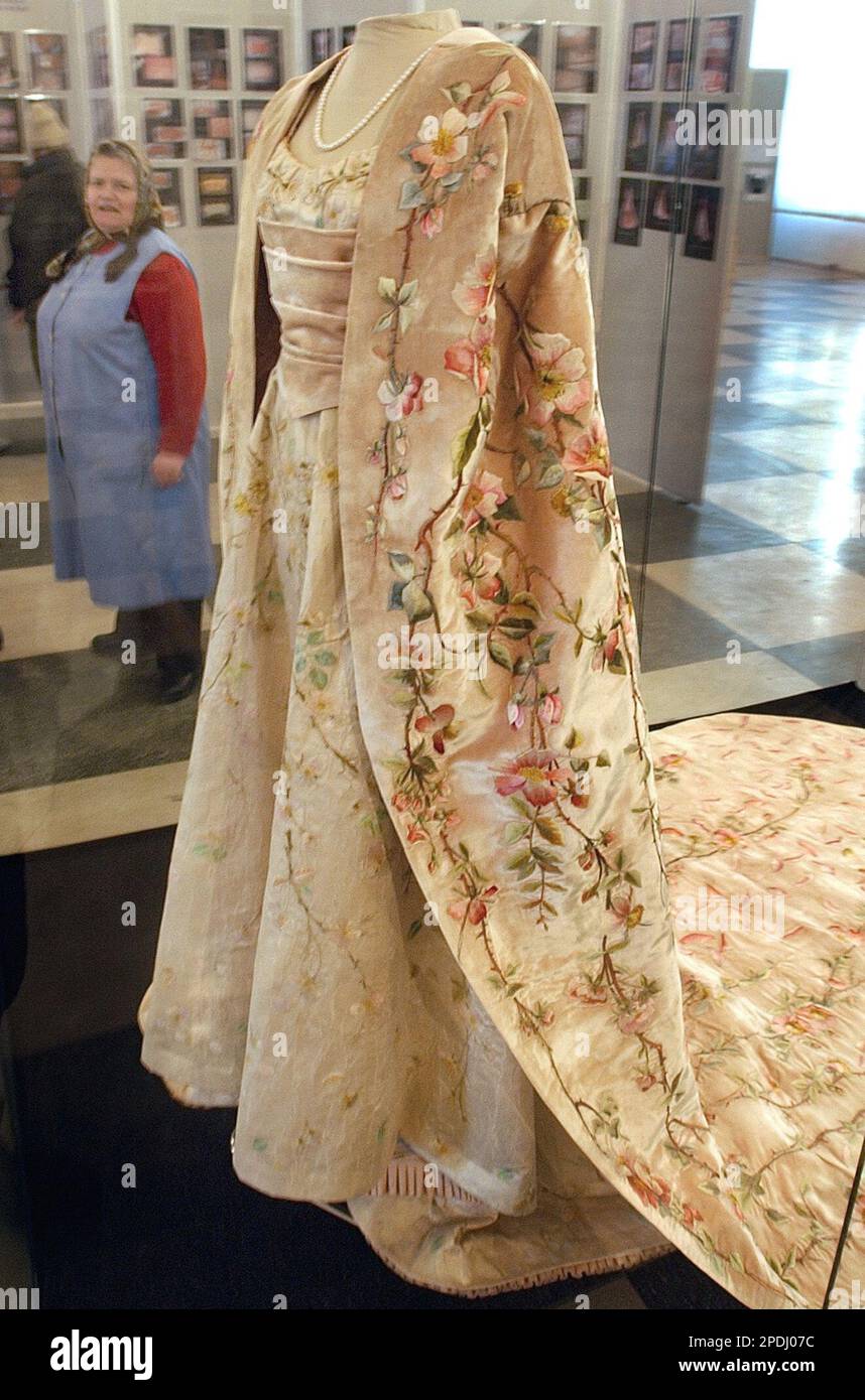 A museum cleaner looks at a gown worn by Romania's former Queen Maria ...