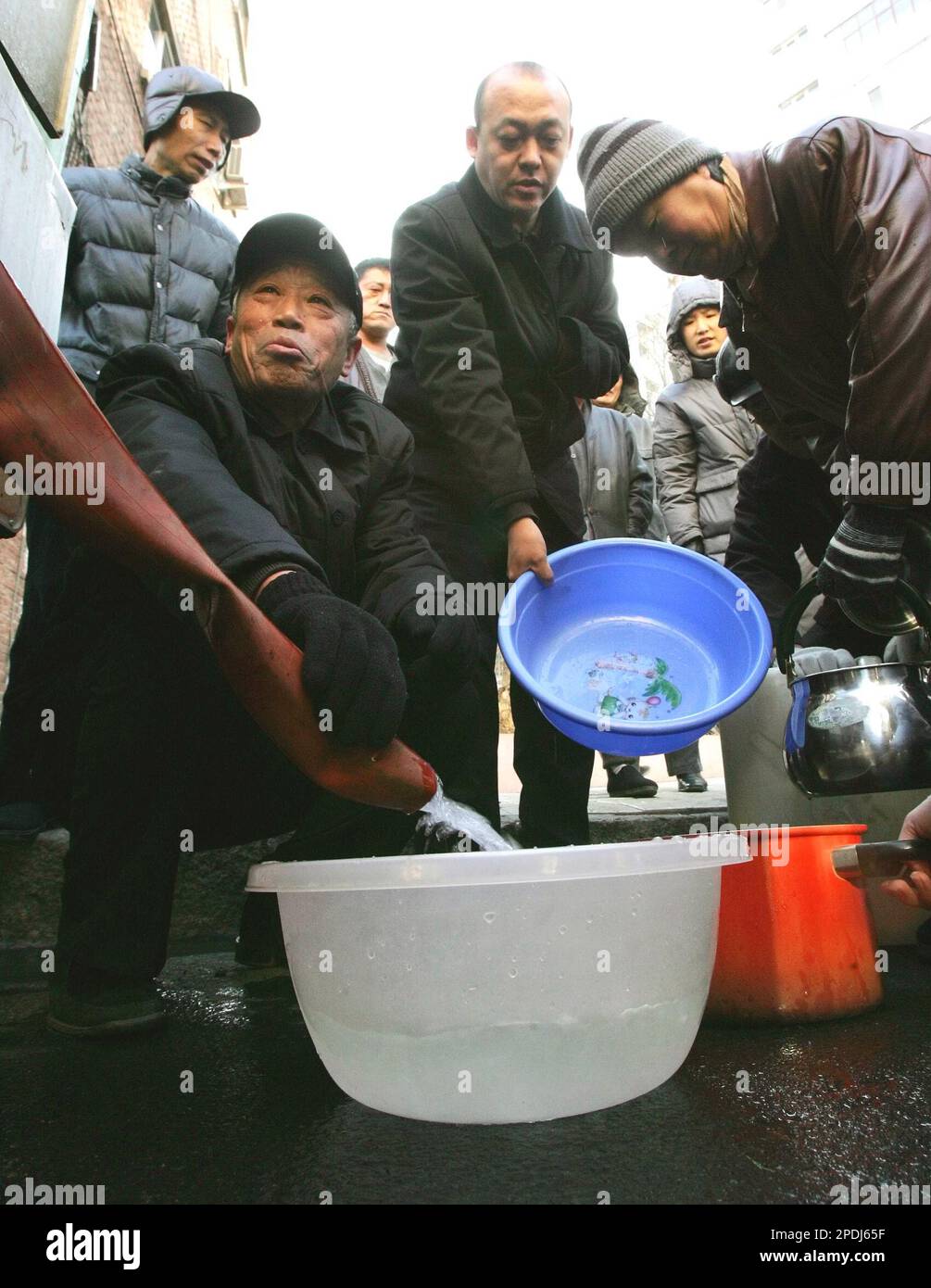 Residents fill water containers from a truck in a street in Harbin, in ...