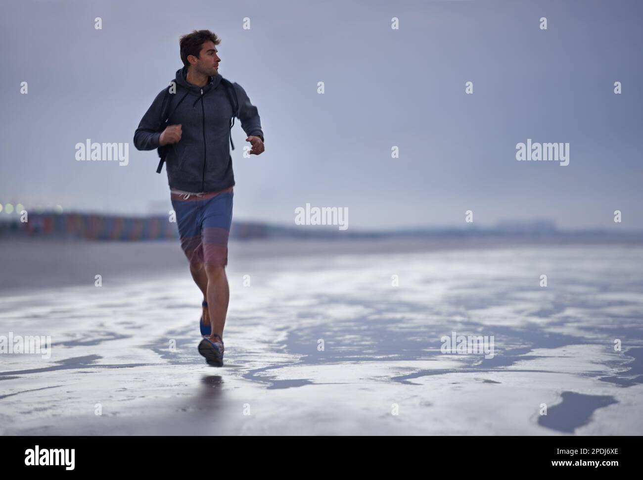 Finding inspiration through fitness. A young man jogging on the beach ...