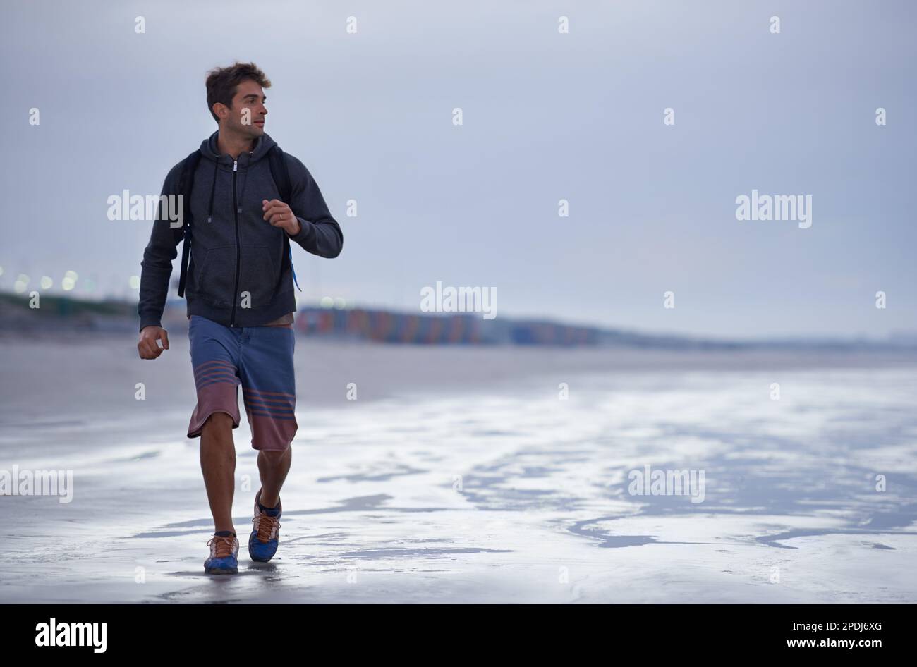 Starting the day with a jog on the beach. A young man jogging on the ...