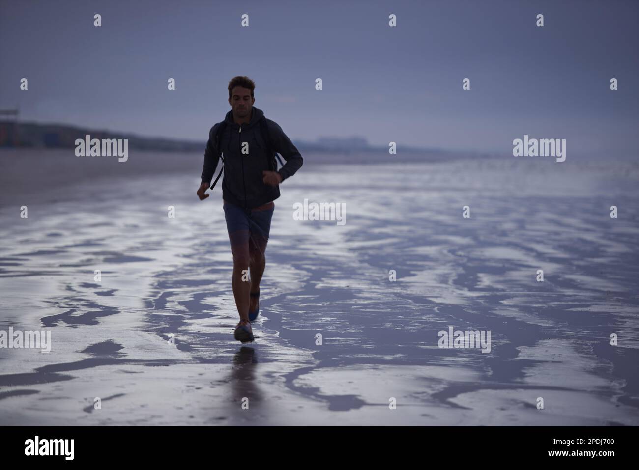 Starting the day with a jog on the beach. A young man jogging on the ...