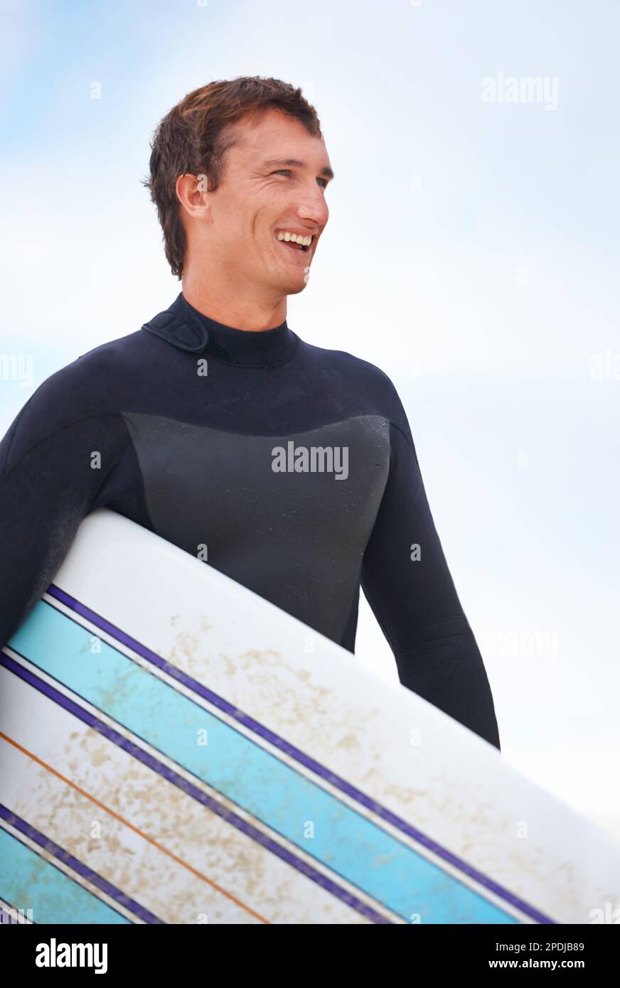 Surfing is a way of life. A young male surfer getting ready to go for a ...