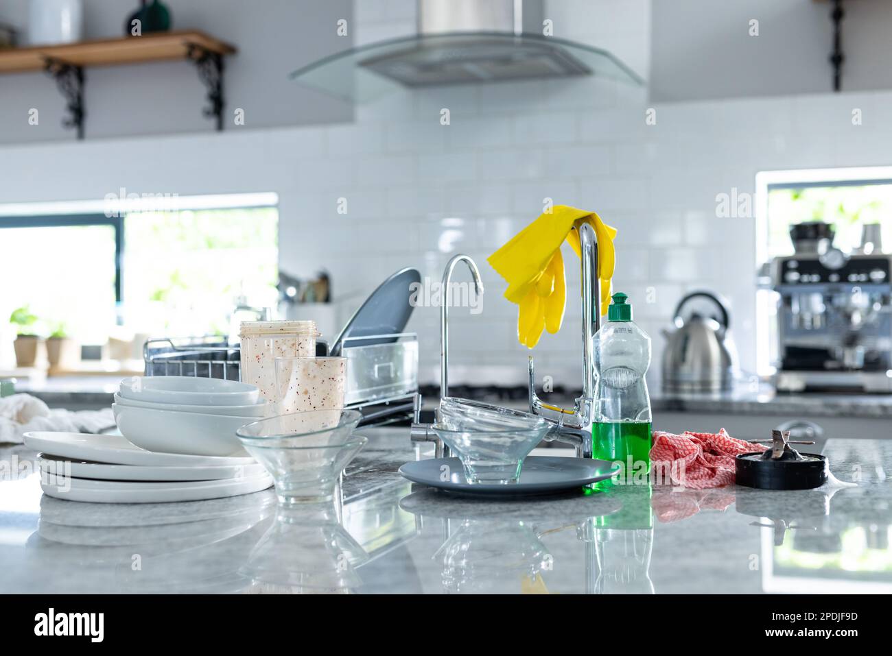Yellow washing up gloves on faucet with dirty dishes and soap dispenser ...
