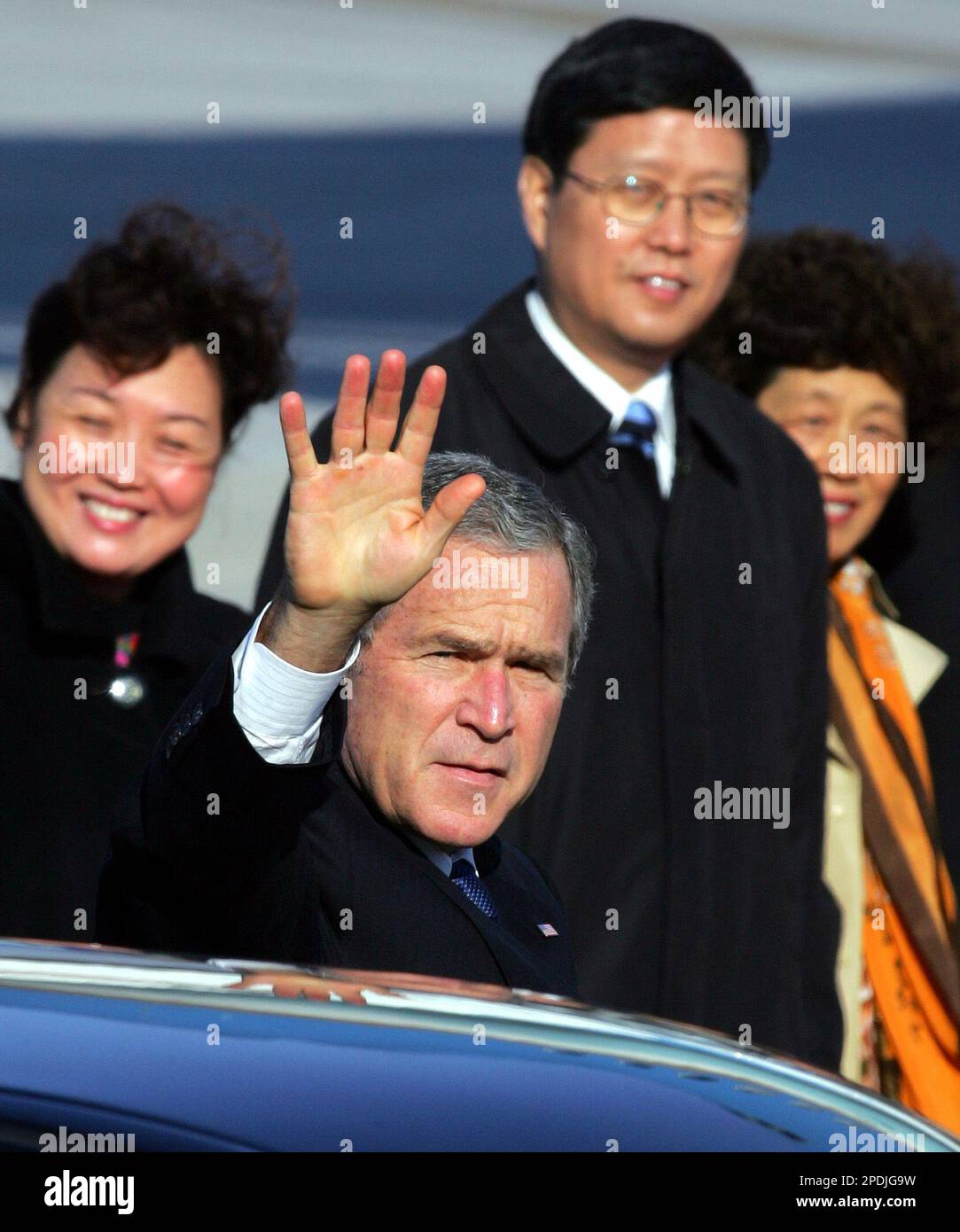 U.S. President George W. Bush waves goodbye as Chinese officials look ...