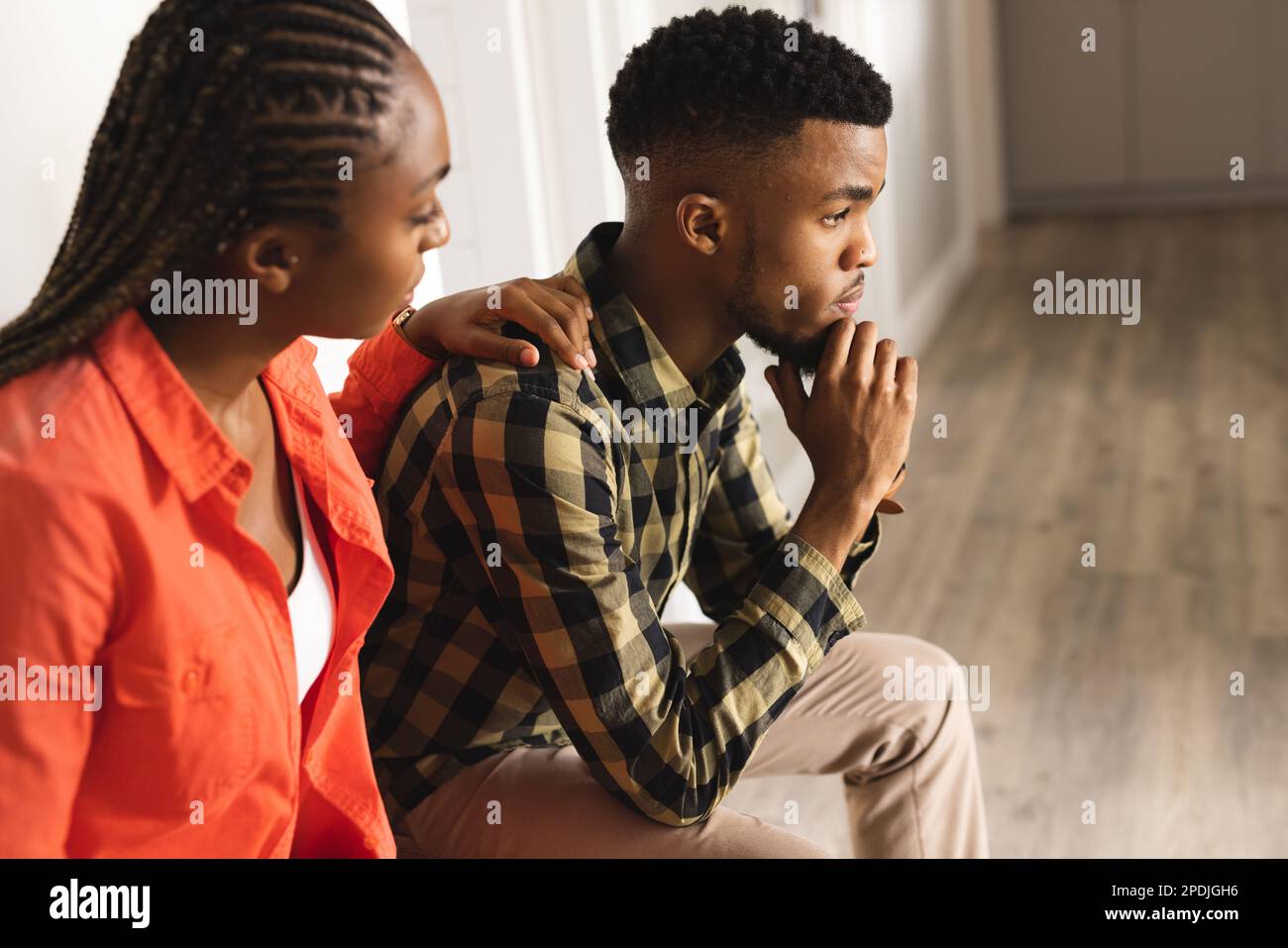 Sad african american couple sitting together in hall Stock Photo - Alamy