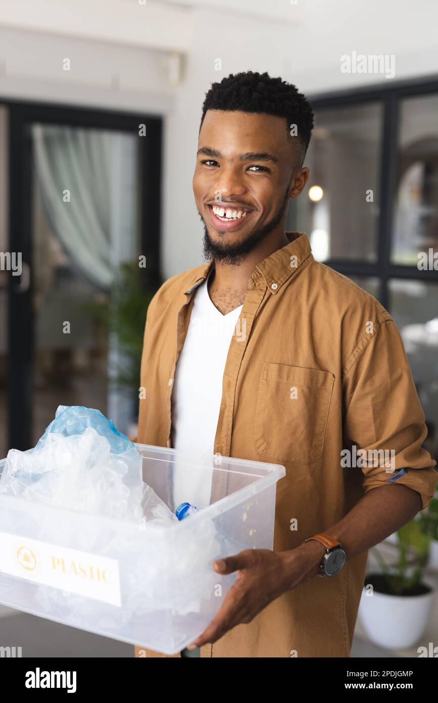 Portrait of happy african american man holding recycling bin Stock ...
