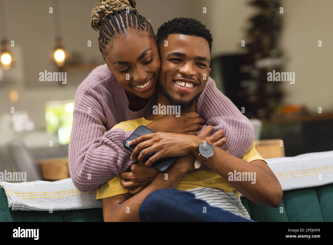 Happy african american couple sitting on sofa and embracing in living ...