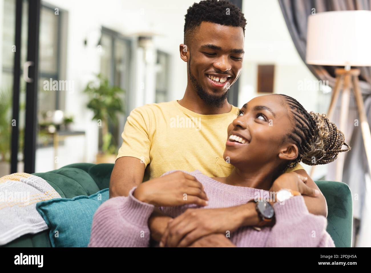 Happy African American Couple Sitting On Sofa And Embracing In Living