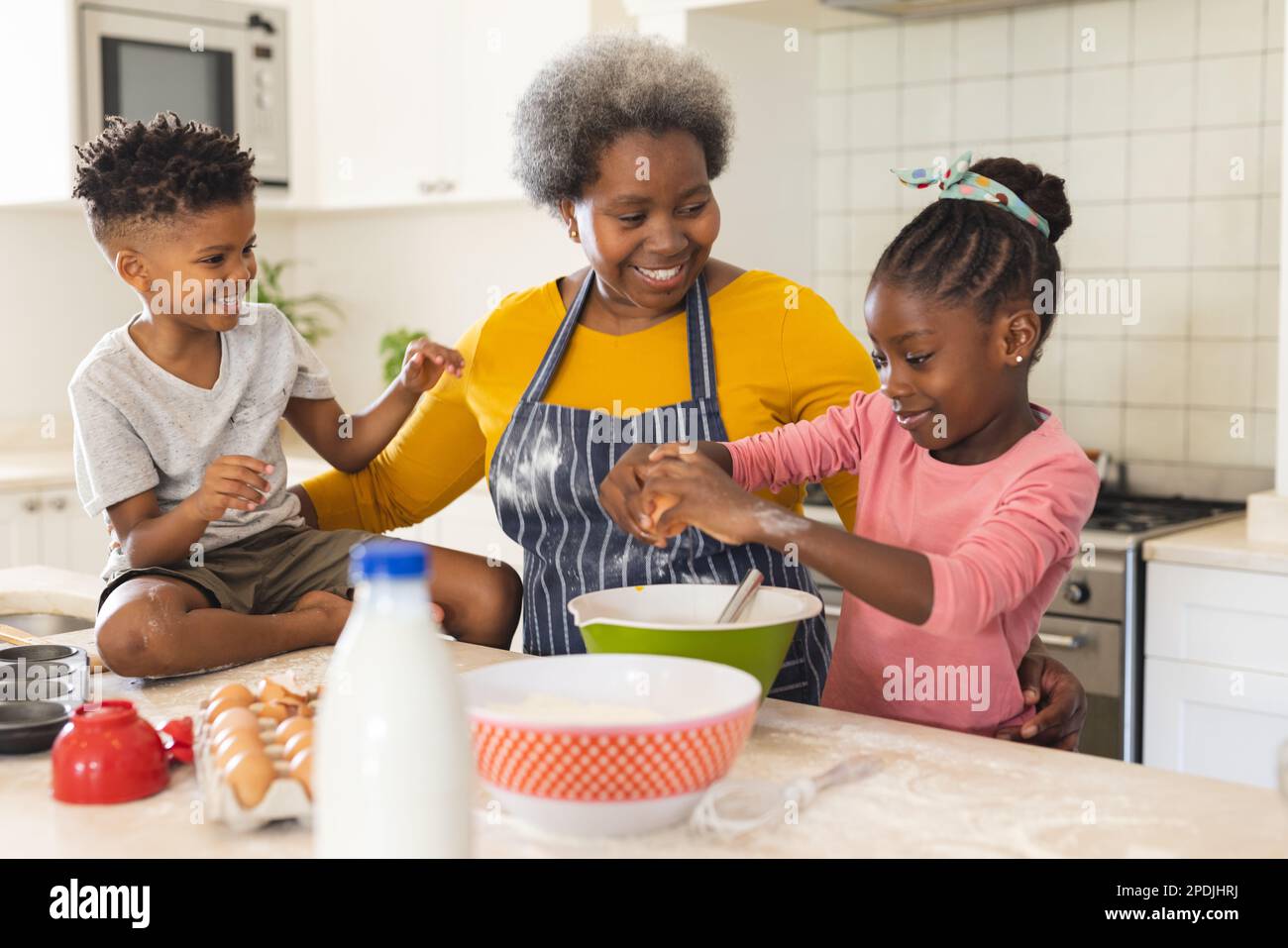 Happy african american grandmother and grandchildren baking together in ...