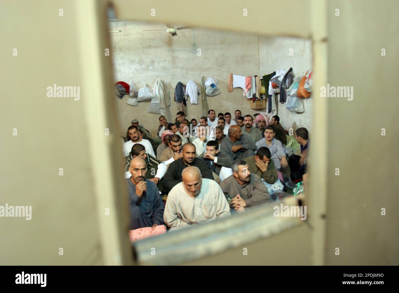 Iraqi detainees are seen through a eyehole as they crowd inside a cell ...