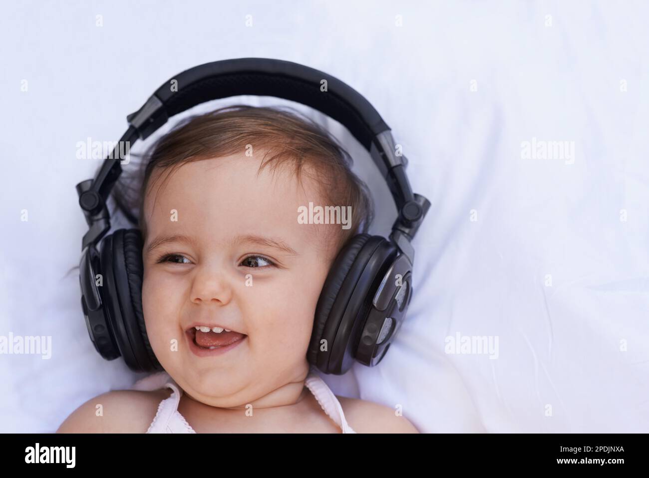Discovering the joys of music. A cute baby girl laughing as she listens ...