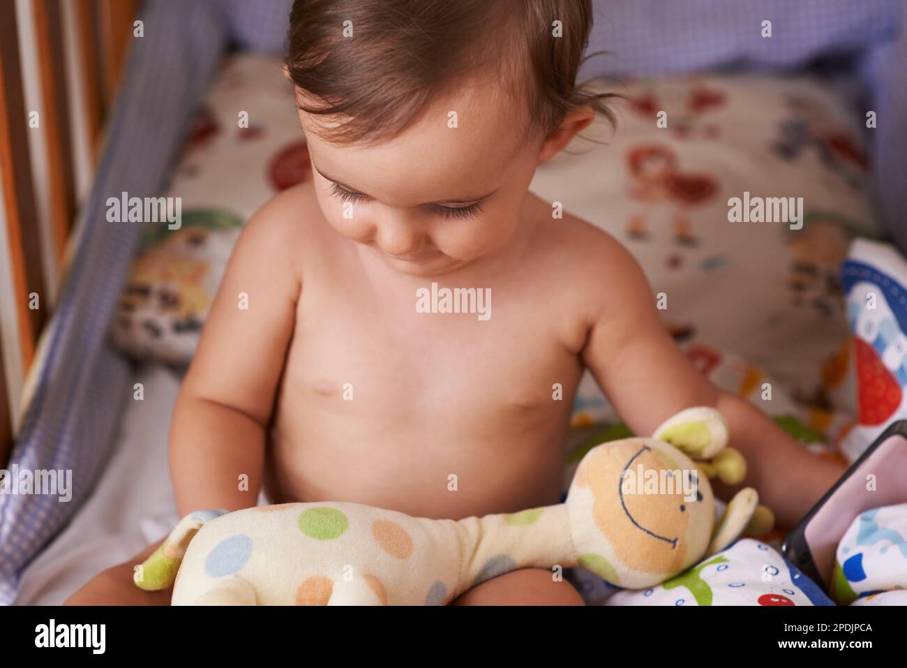 She loves her fluffy giraffe. A cute little baby girl in her crib at ...