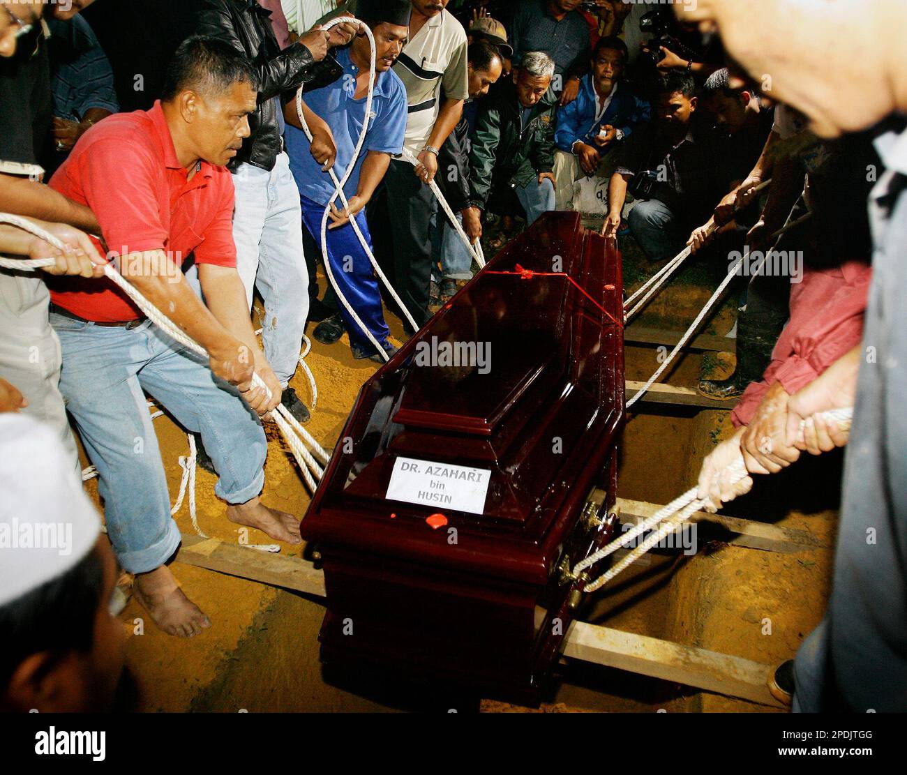 Villagers lower Azahari bin Husin's coffin for burial near his mother's ...