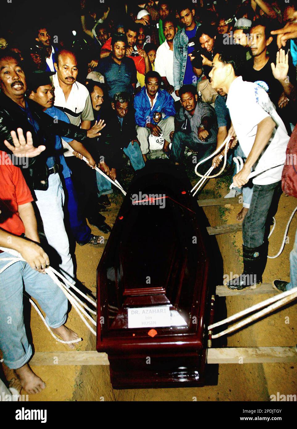 Villagers lower Azahari bin Husin's coffin for burial near his mother's ...