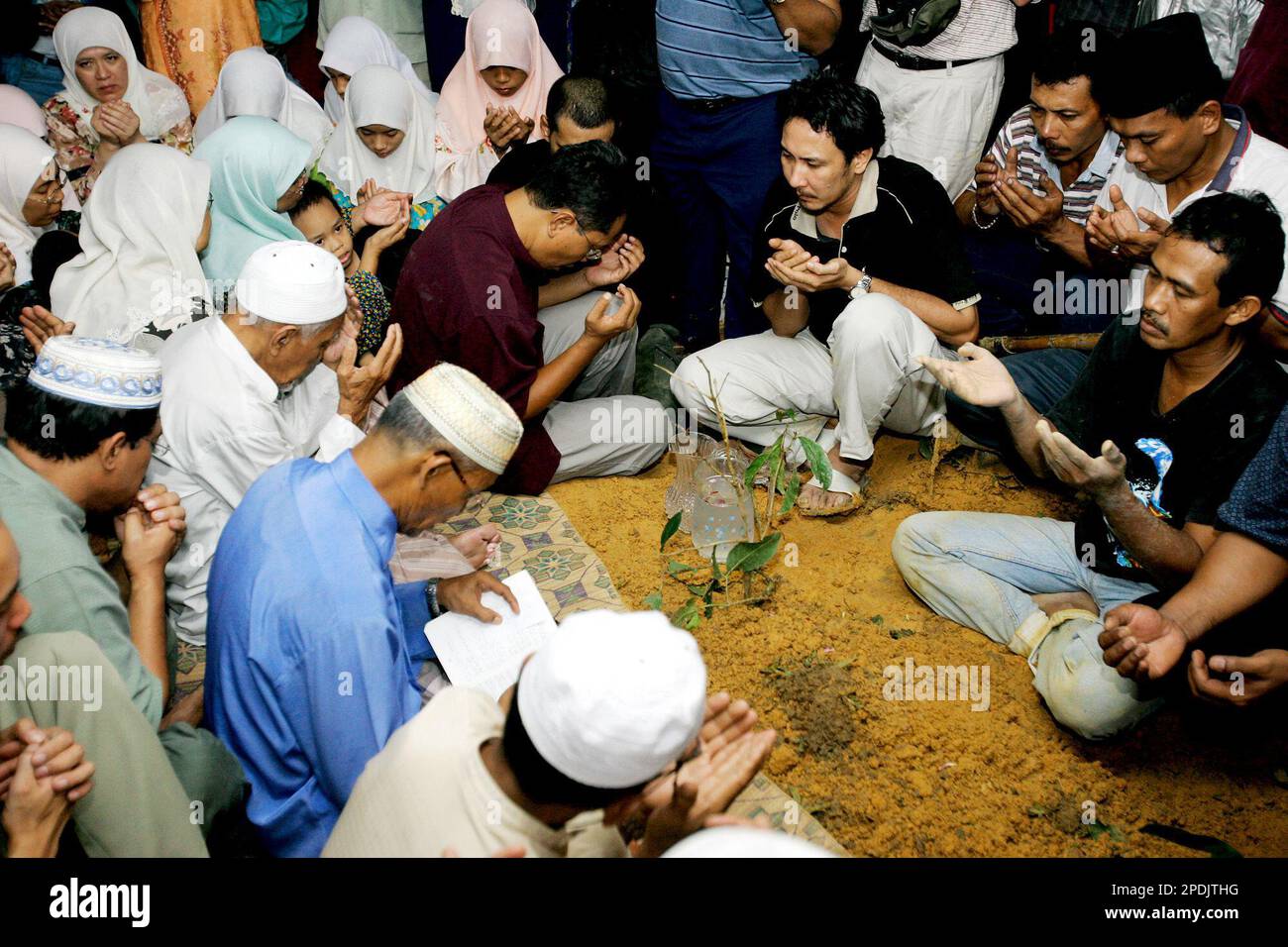 Relatives of Azahari bin Husin offer prayers after his body was buried ...