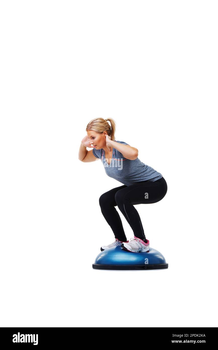 She works out daily. A young woman standing on a bosu-ball while ...