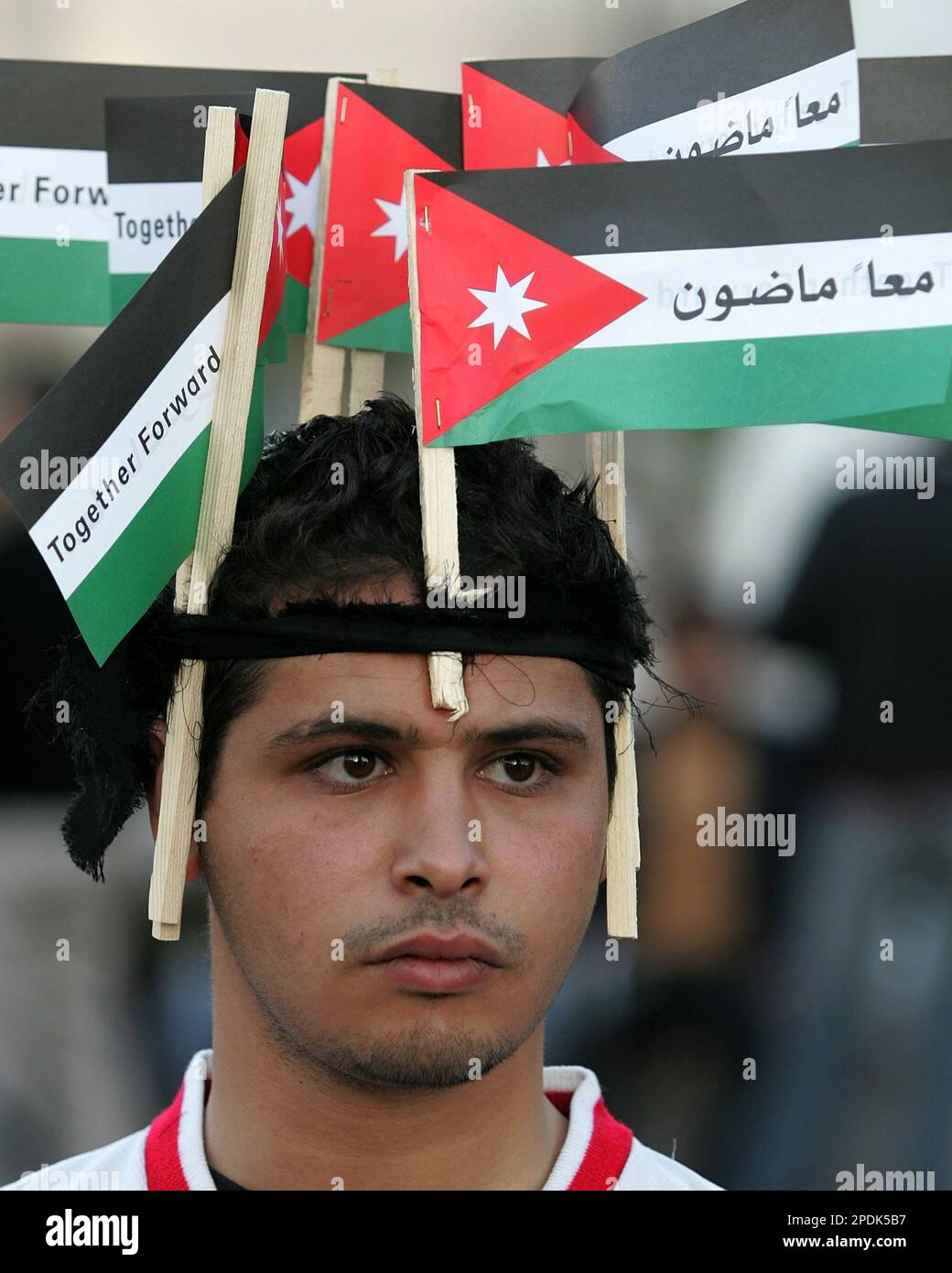 A Jordanian man with Jordanian flags attached to his head in front of ...