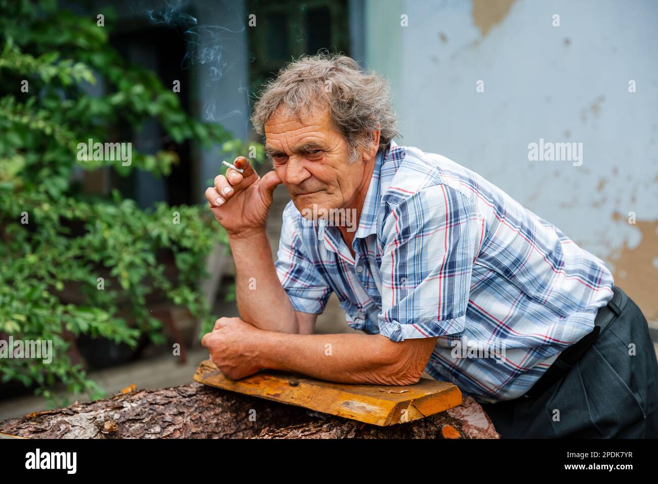 Serious senior man standing and smoking a cigarette. Portrait of man ...