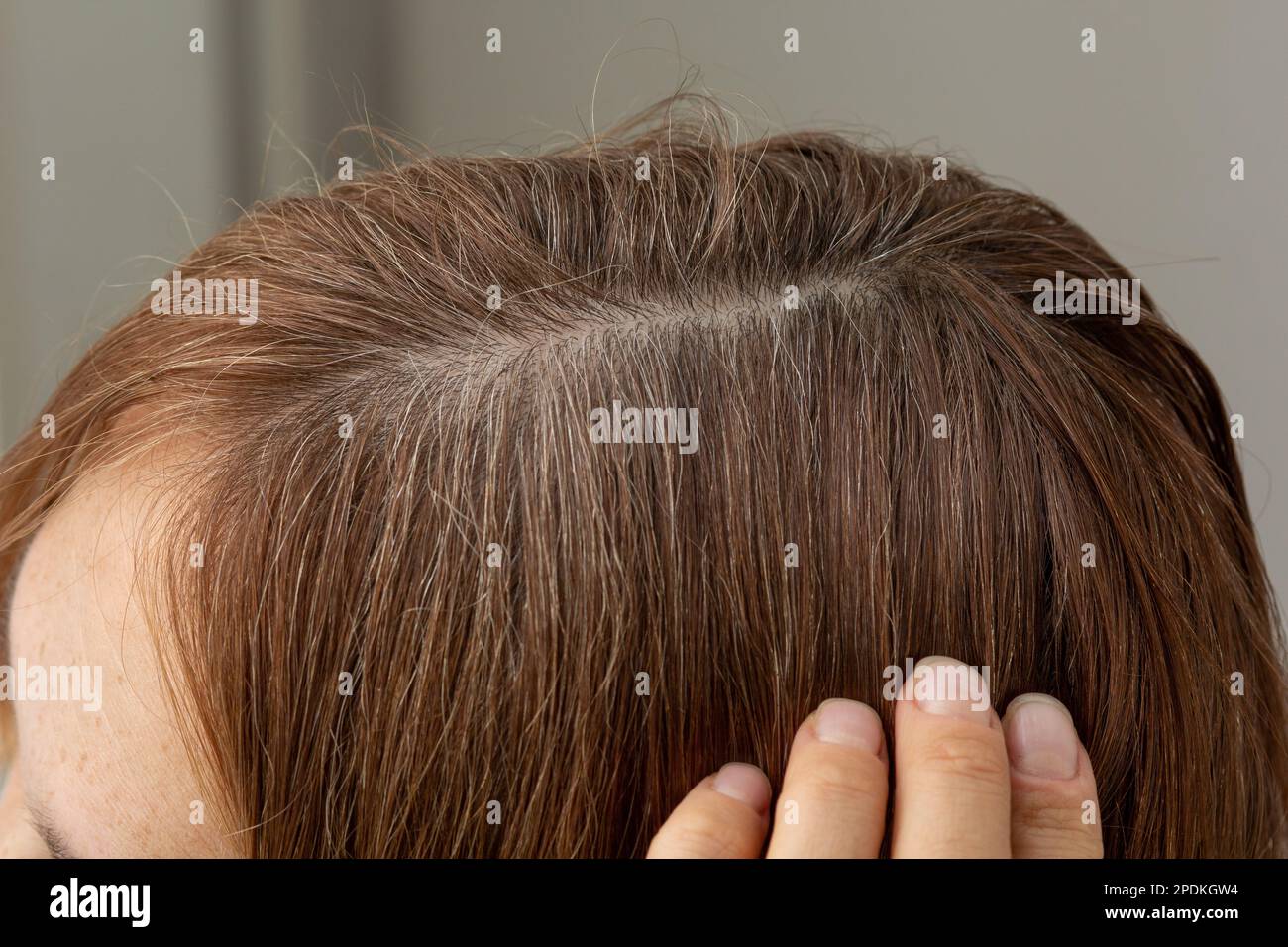 Close up head with gray hair on roots along hair parting before ...