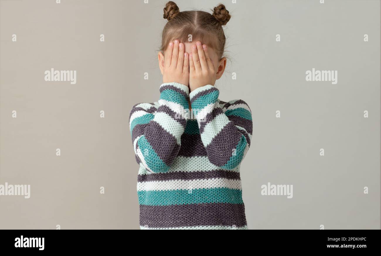Child placing hands across face to express embarrassment dismay or fear ...