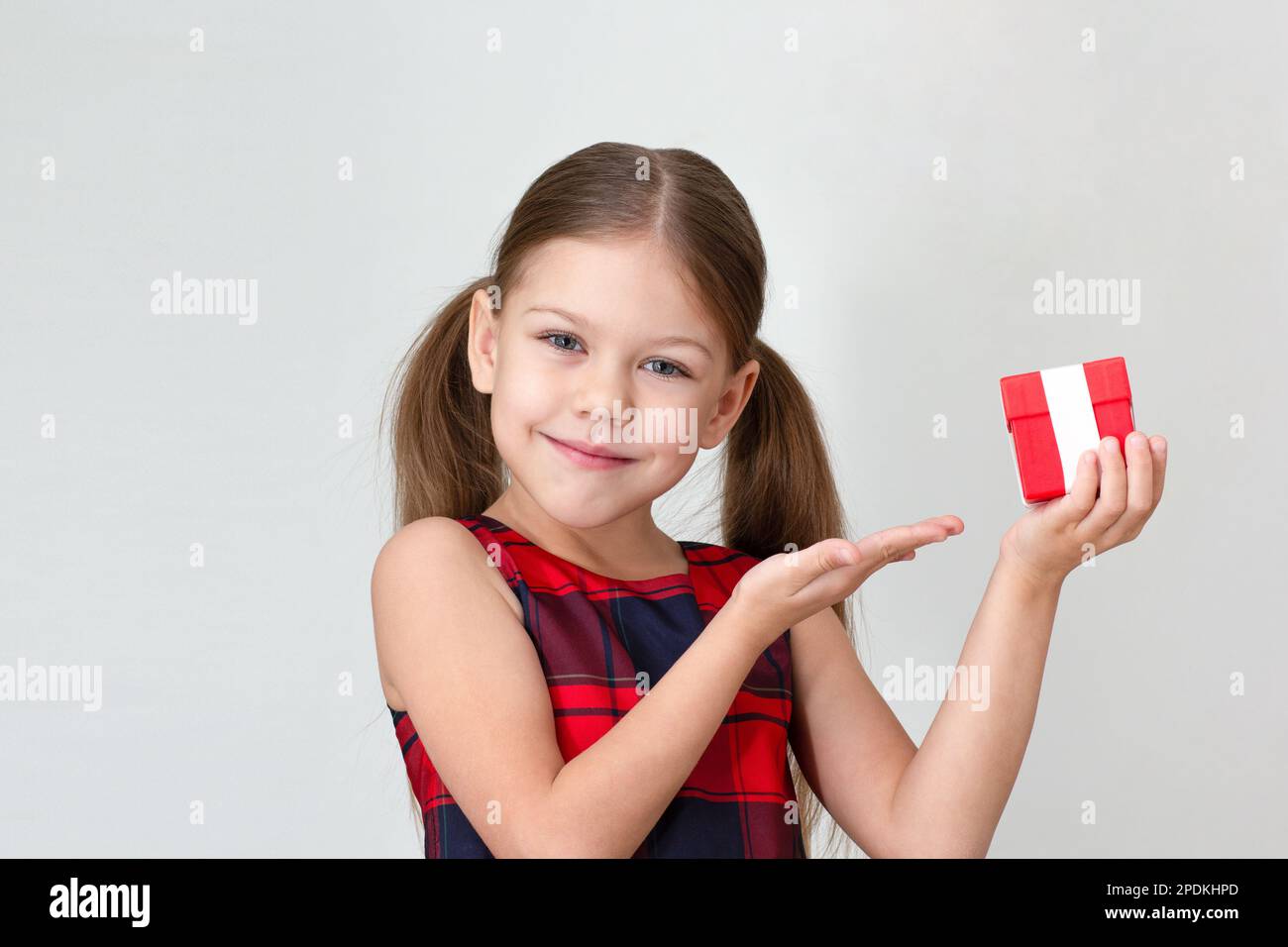 Happy and smiling child holding little box as present and showing on it ...