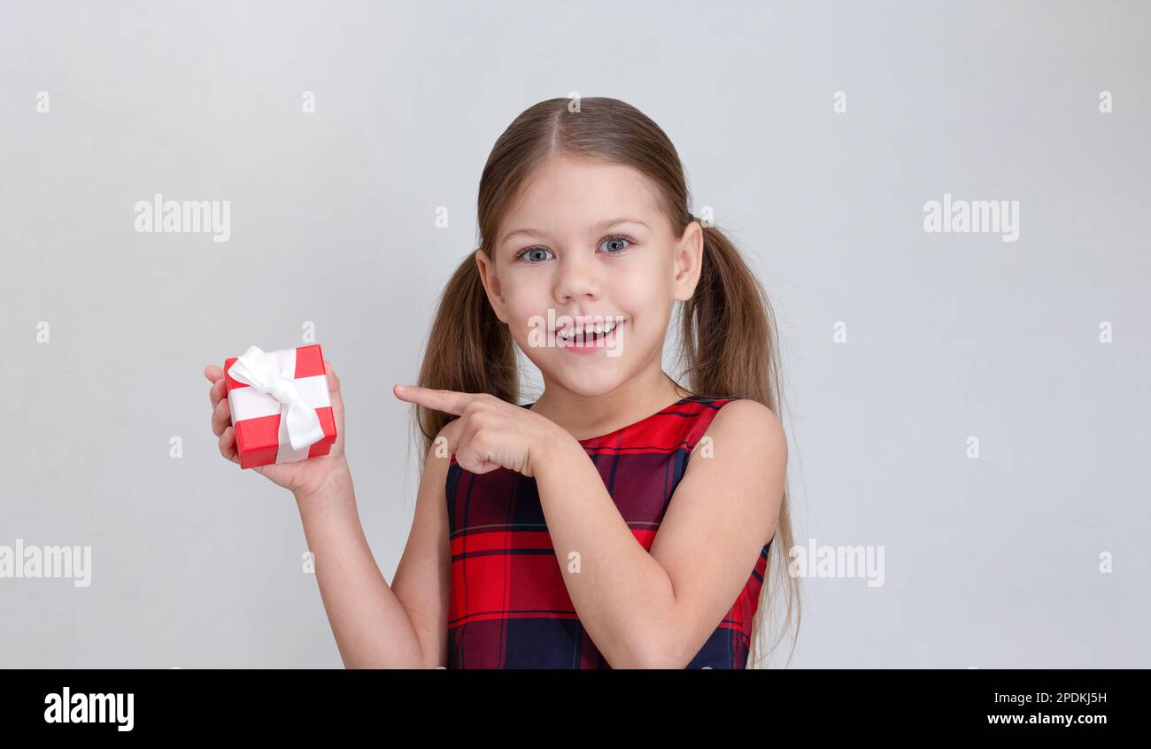 Happy and smiling child holding little box as present and showing on it ...