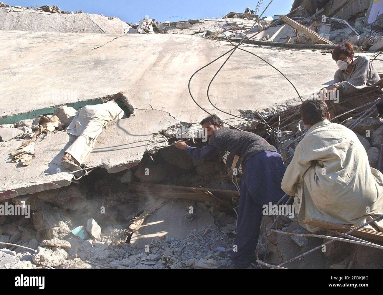 Pakistani volunteers remove debris to recover a dead body from a ...
