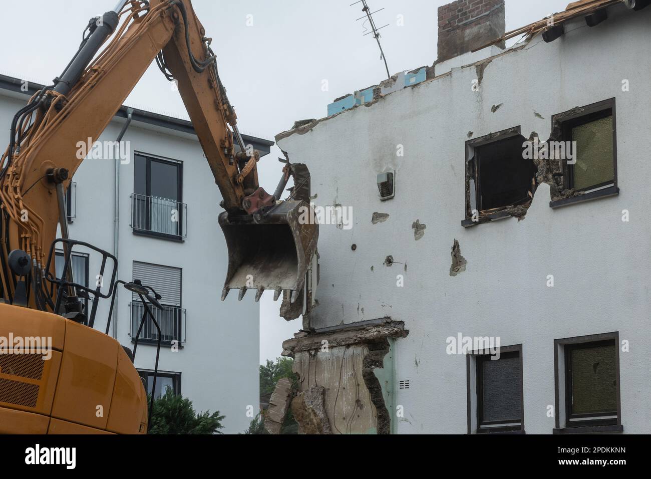 Demolition of a building. An excavator breaks an old house. A new house ...