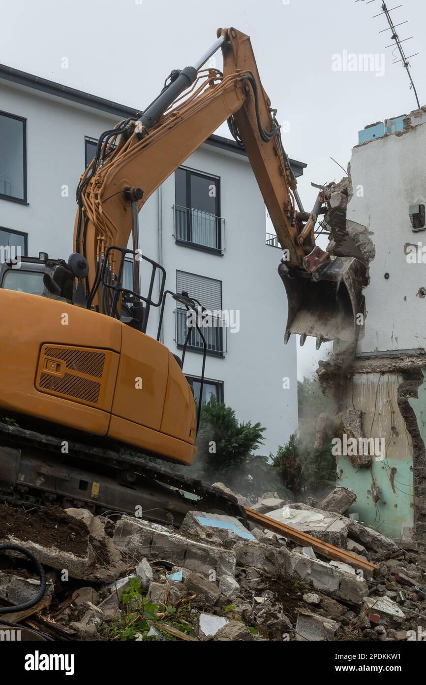 Demolition of a building. An excavator breaks an old house. A new house ...