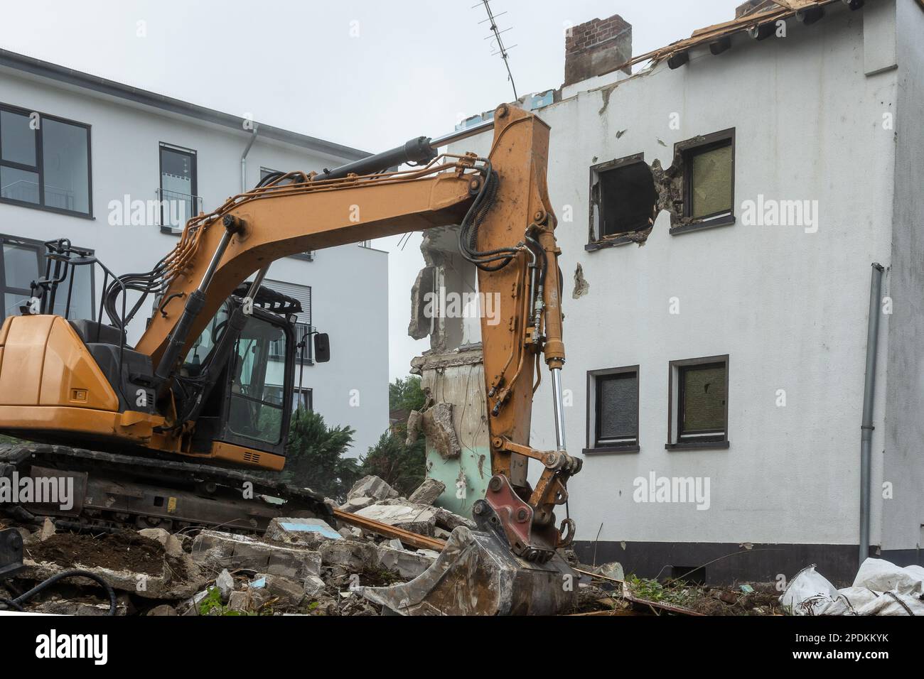 Demolition of a building. An excavator breaks an old house. A new house ...