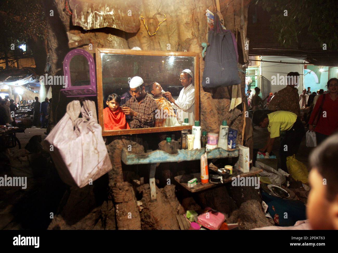 Reflected in a mirror a Muslim man and his son get a hair cut at a ...