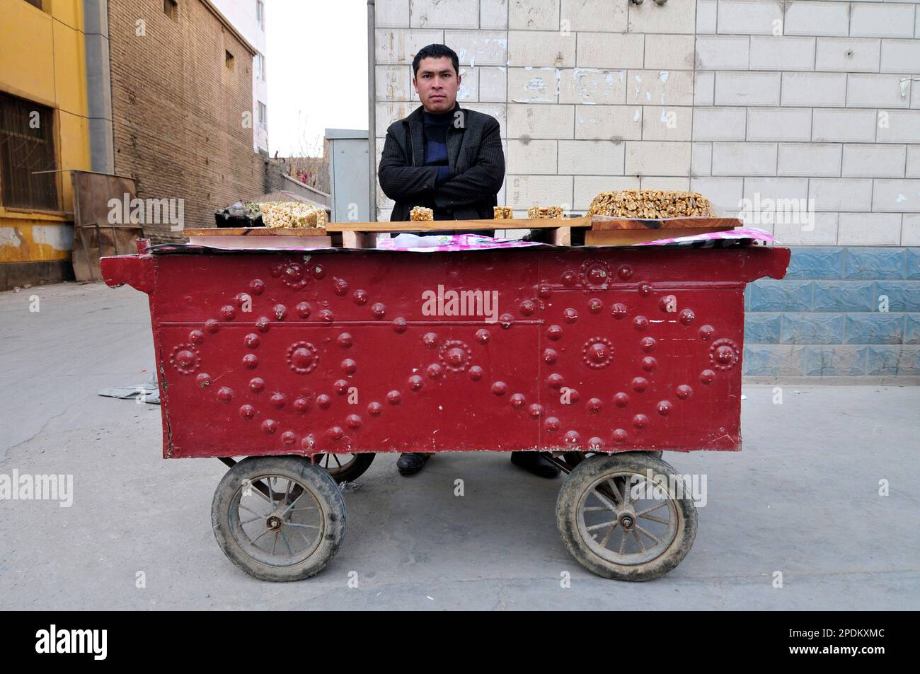 An Uyghur man selling traditional nuts candies from his mobile cart in ...