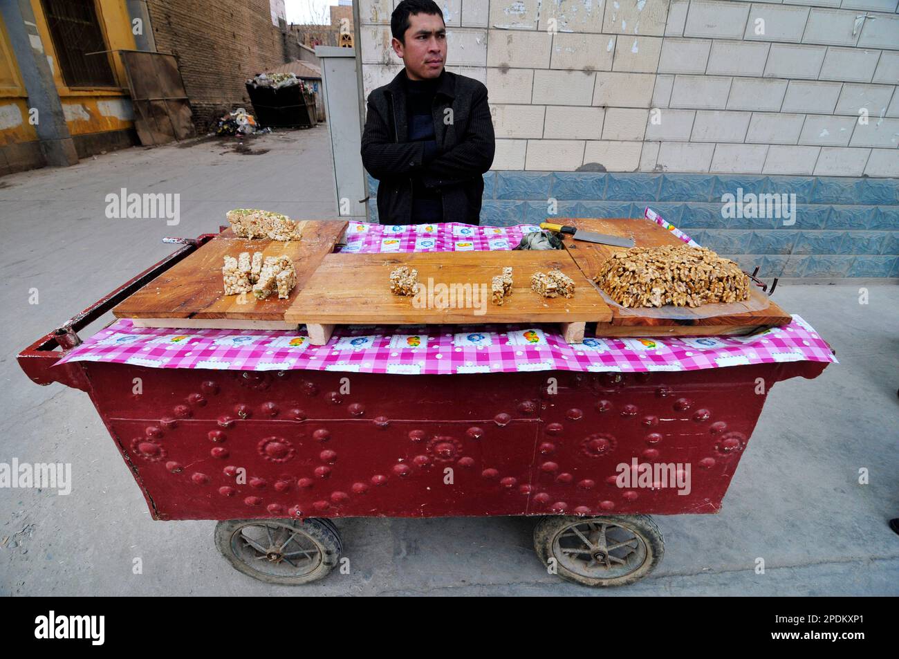 An Uyghur man selling traditional nuts candies from his mobile cart in ...