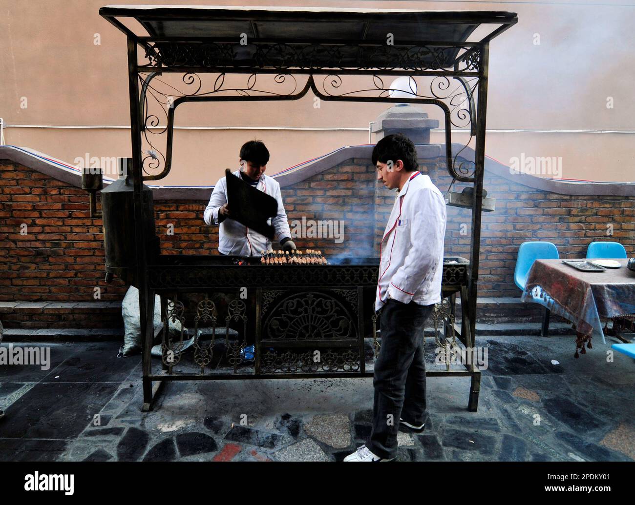 An Uyghur man grilling kebabs ( meat skewers ) in the old city of ...
