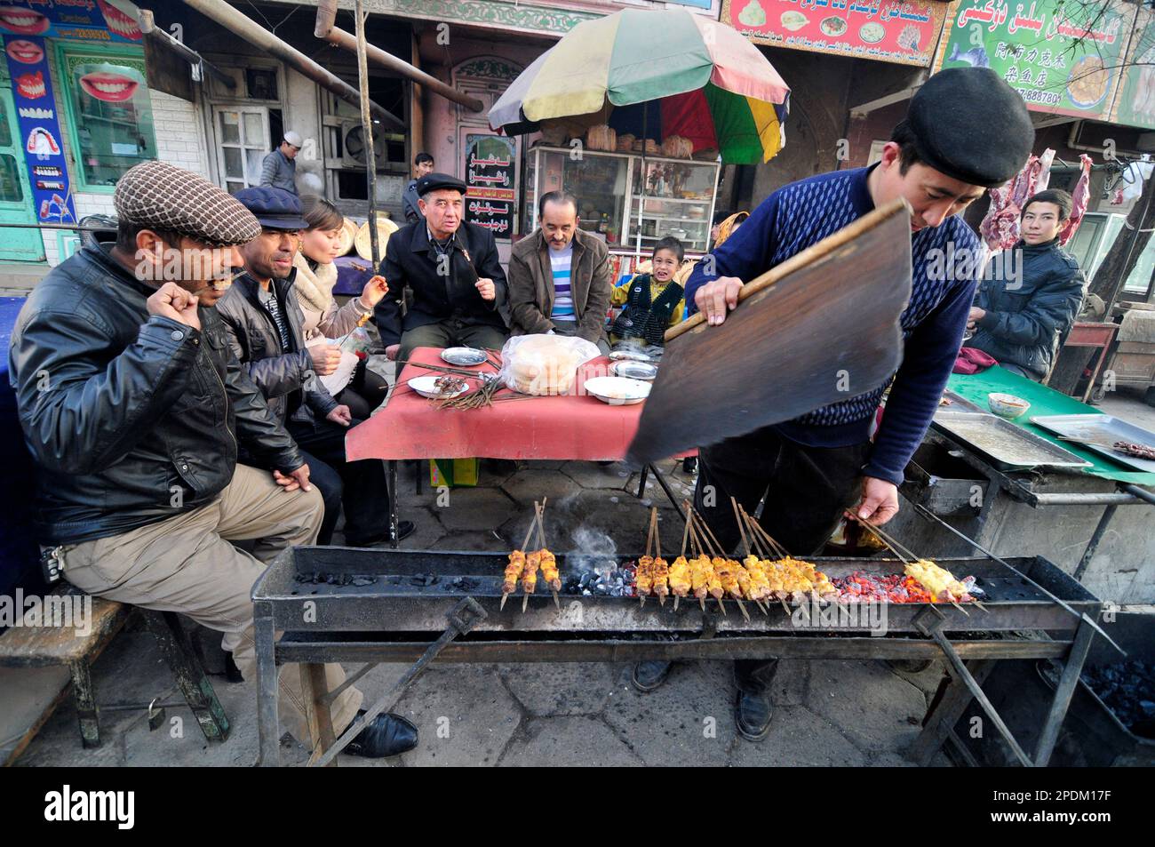 An Uyghur man grilling kebabs ( meat skewers ) in the old city of ...