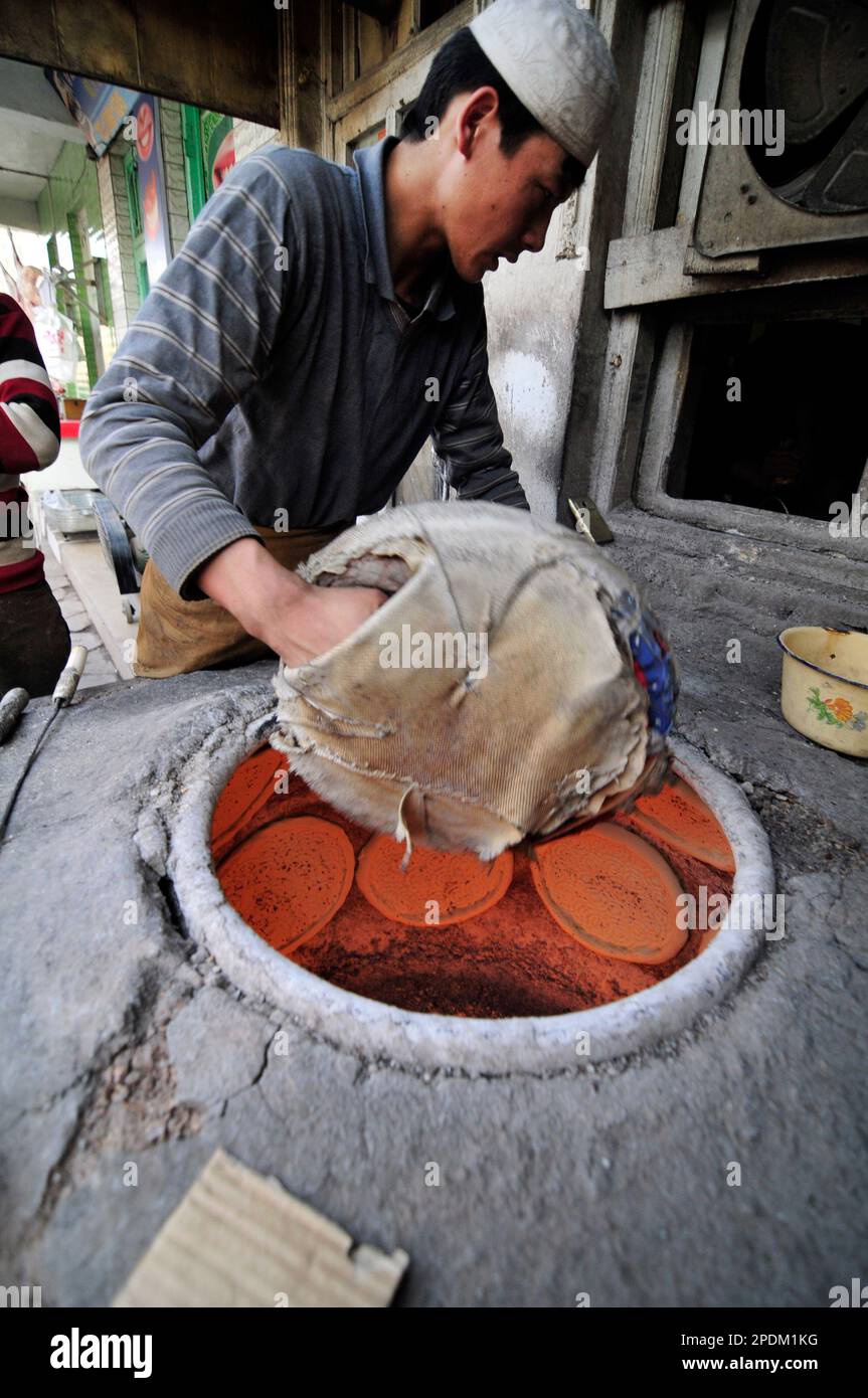 An Uyghur man baking the Naan bread in a tandoor oven in the old city ...