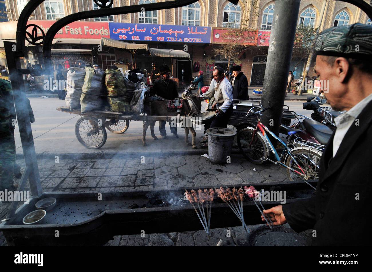An Uyghur man grilling kebabs ( meat skewers ) in the old city of ...
