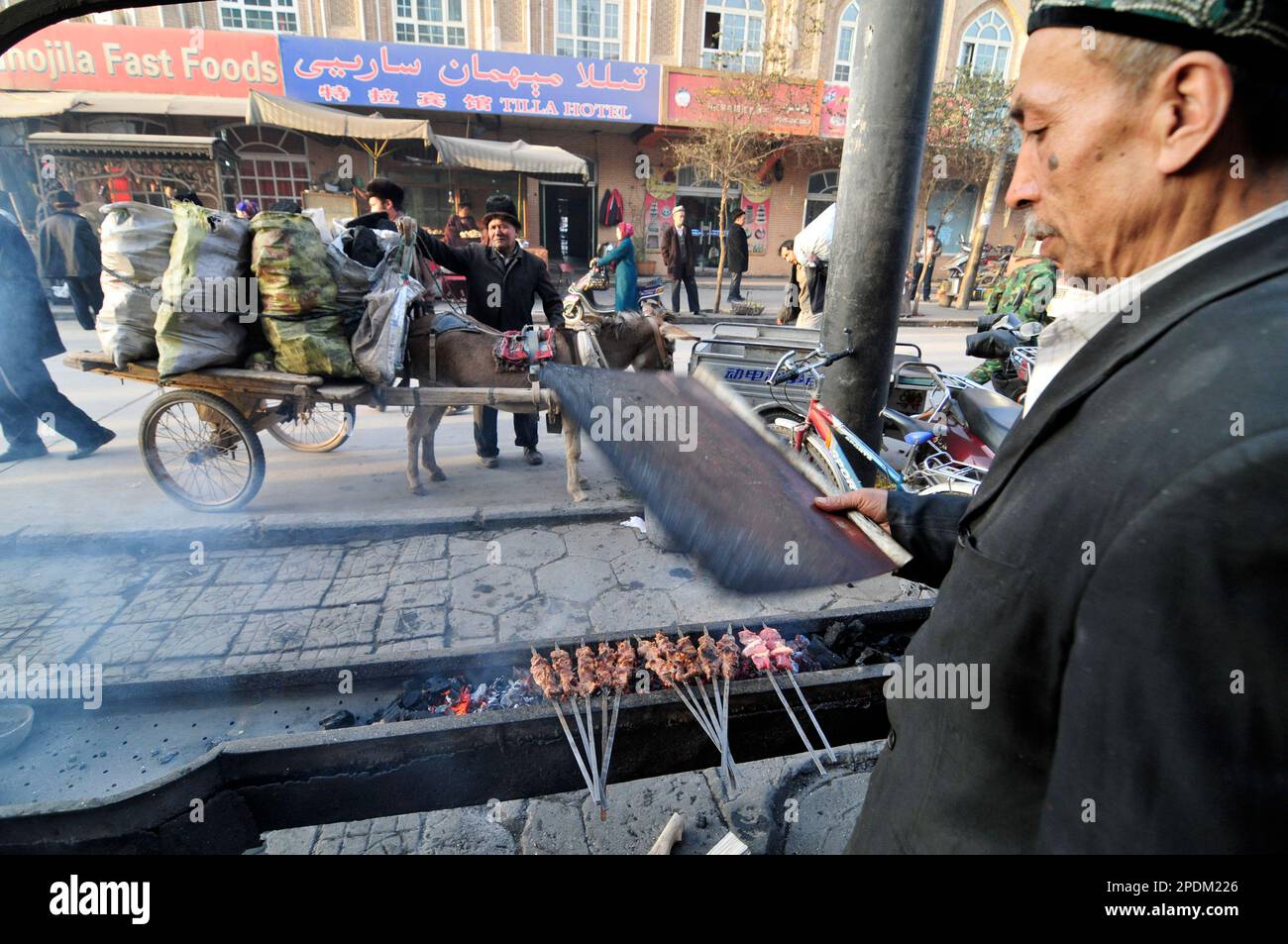An Uyghur man grilling kebabs ( meat skewers ) in the old city of ...