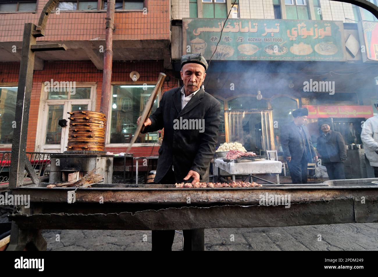 An Uyghur man grilling kebabs ( meat skewers ) in the old city of ...