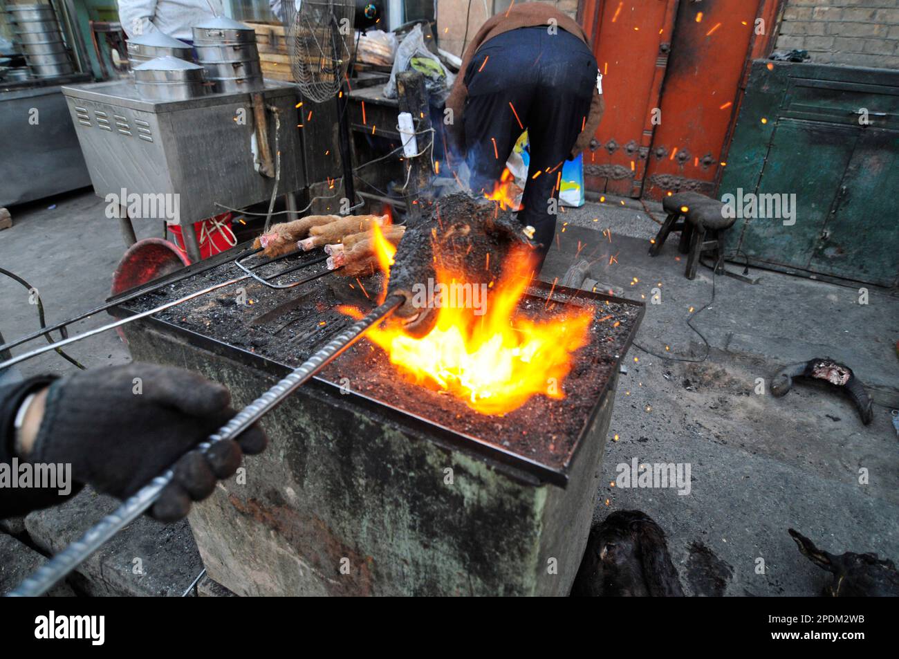An Uyghur man burning the hair off a sheep's head in the street in the ...