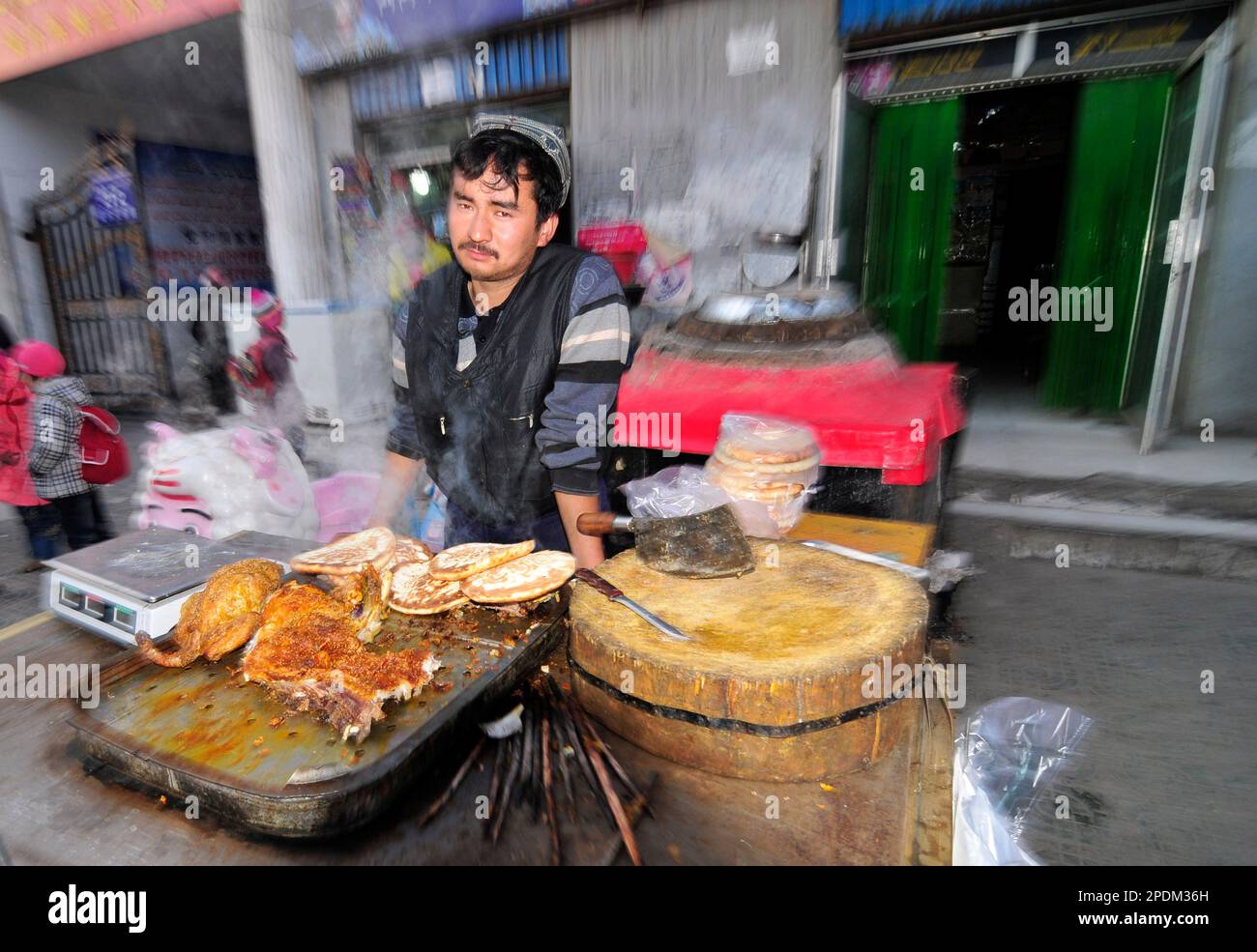 An Uyghur man selling chopped grilled meat with Naan bread in the old ...