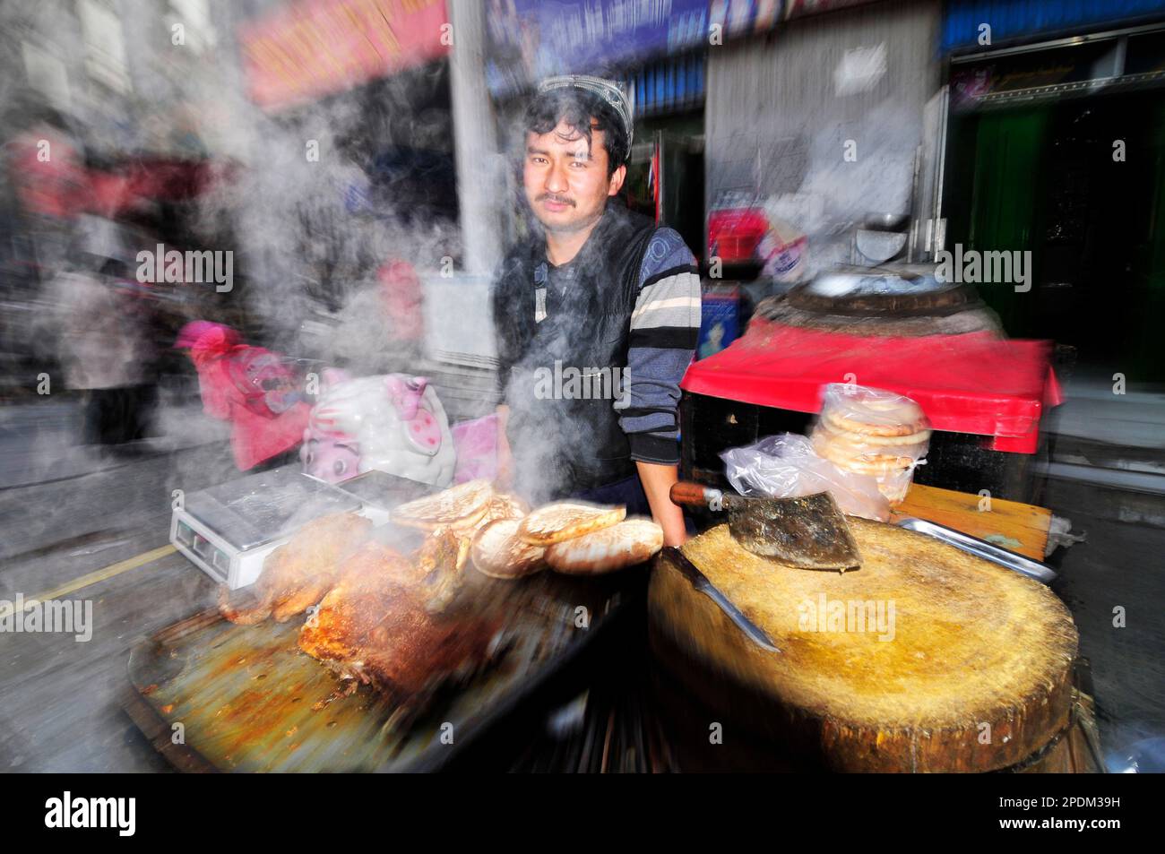 An Uyghur man selling chopped grilled meat with Naan bread in the old ...