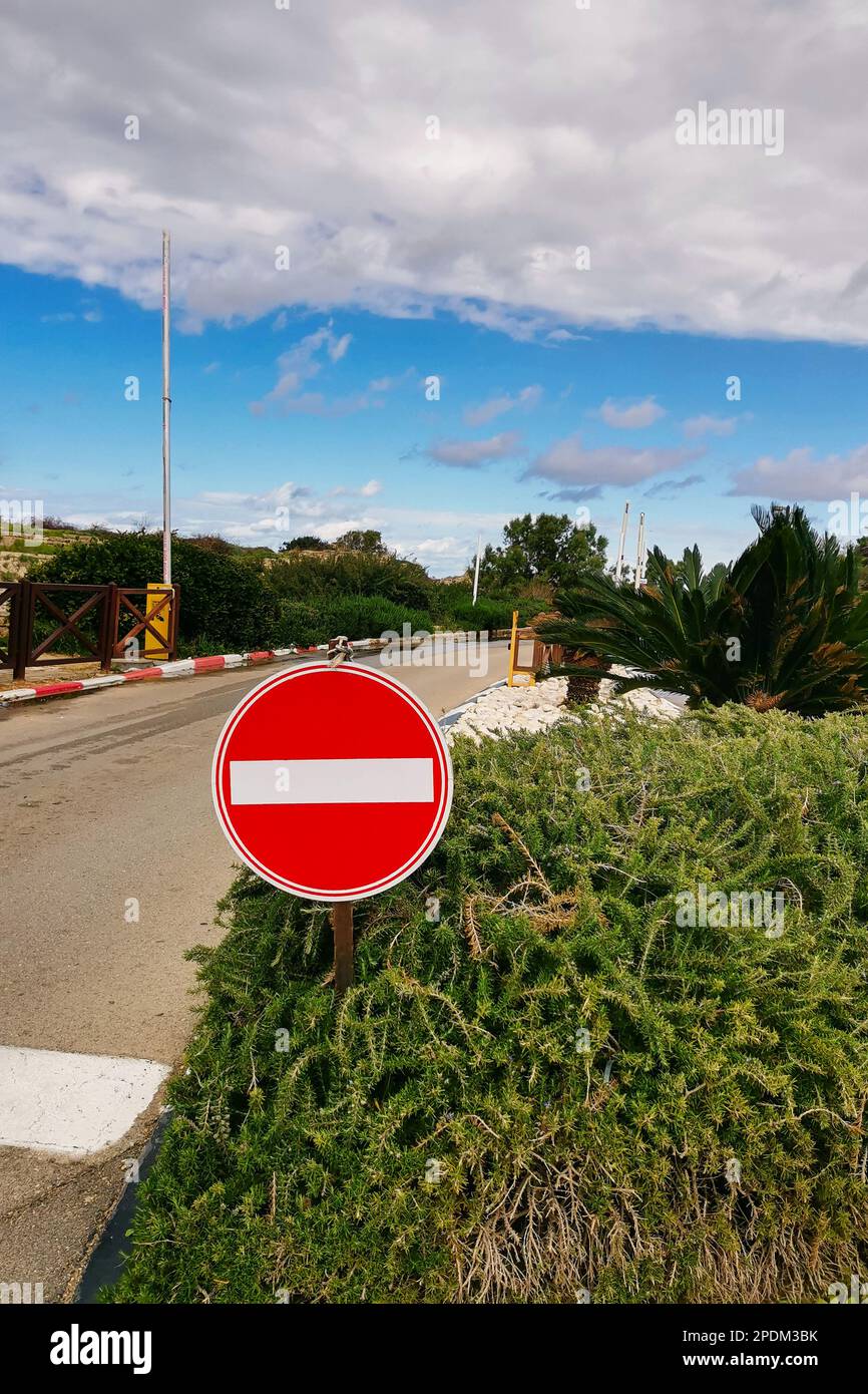 No Entry road sign against cloudy blue sky on urban street. Road closed ...