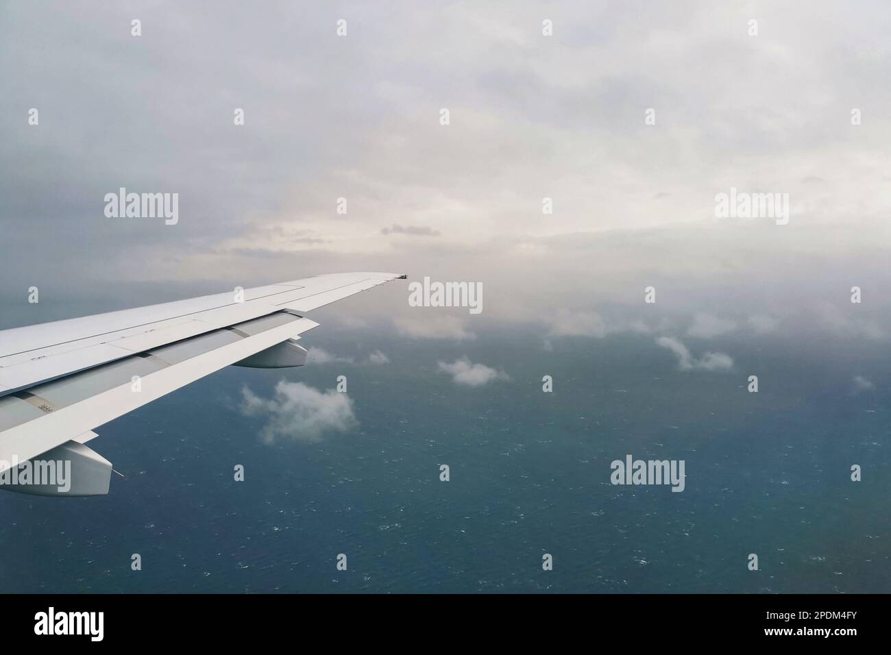 Plane is landing. Airplane wing over sea and clouds. Aerial view ...