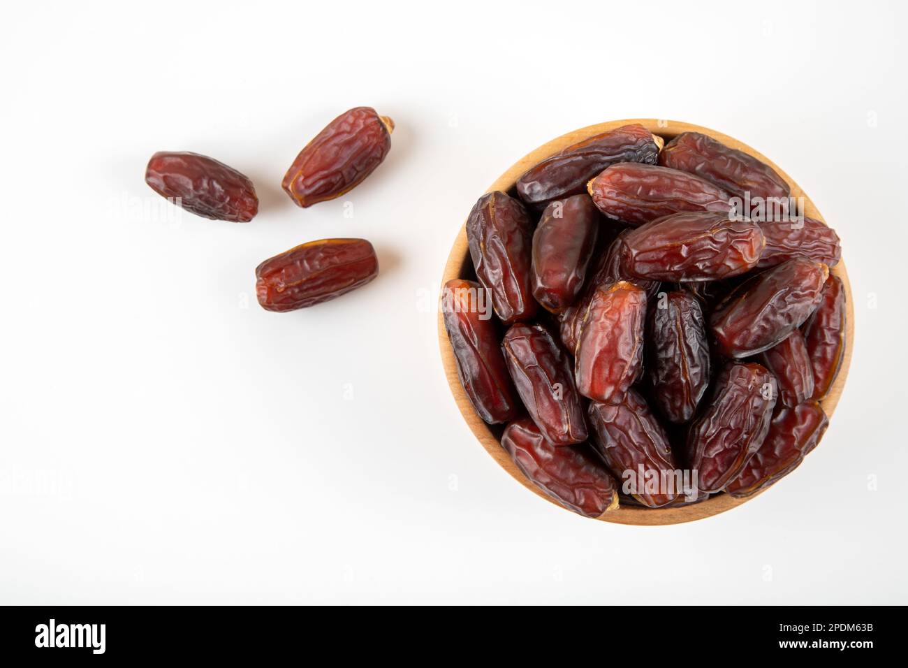 Date fruits in wooden bowl,on white background,top view Stock Photo - Alamy