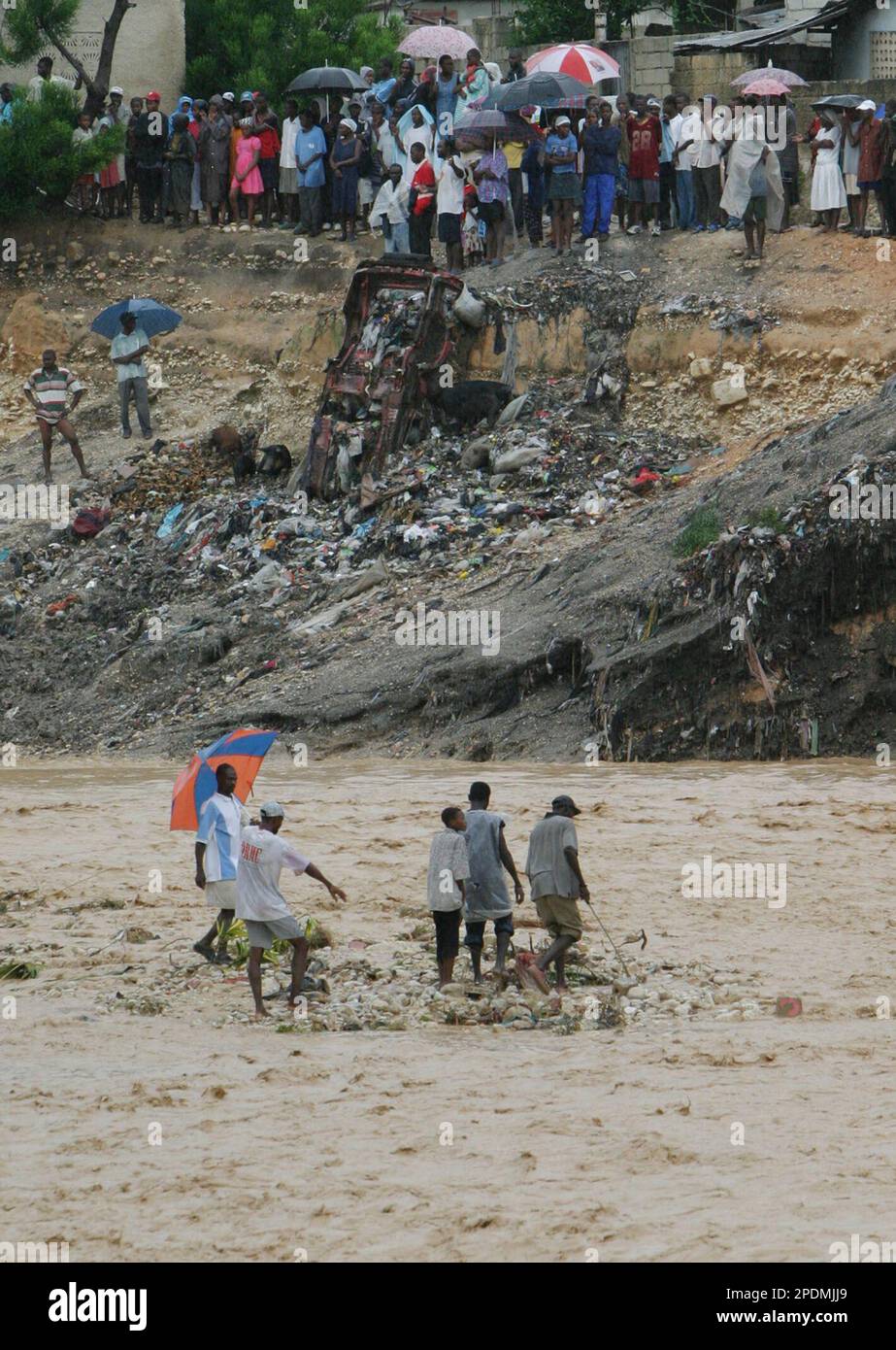 Residents in Carrefour cross an over flowed river as others stand on ...