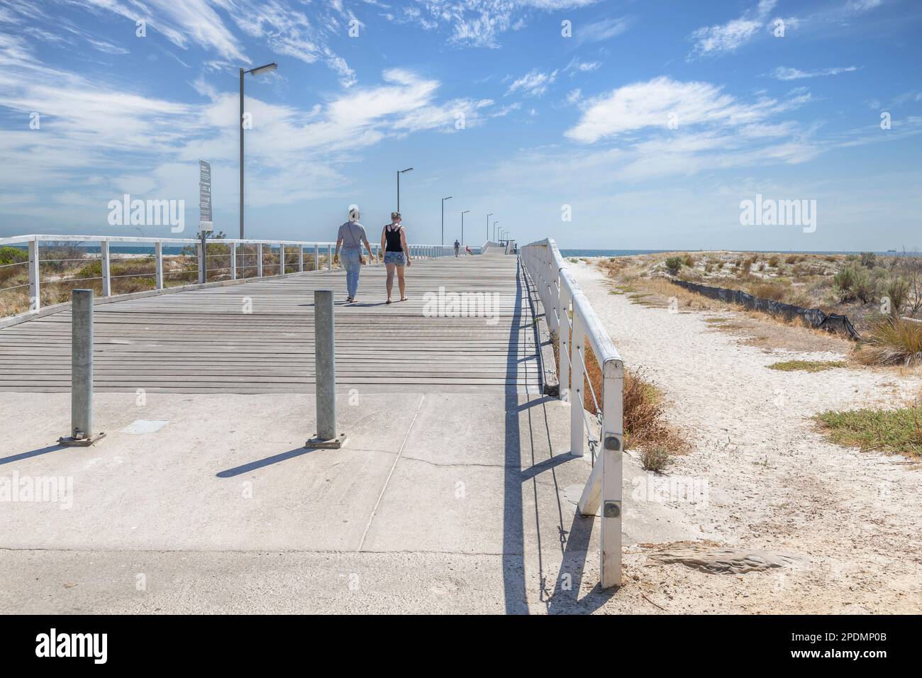 two people walking on the boardwalk to the beach Stock Photo - Alamy